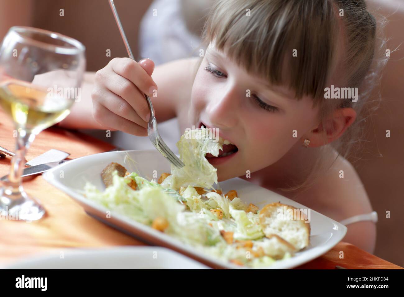The girl bites leaf of cabbage from Caesar salad Stock Photo - Alamy