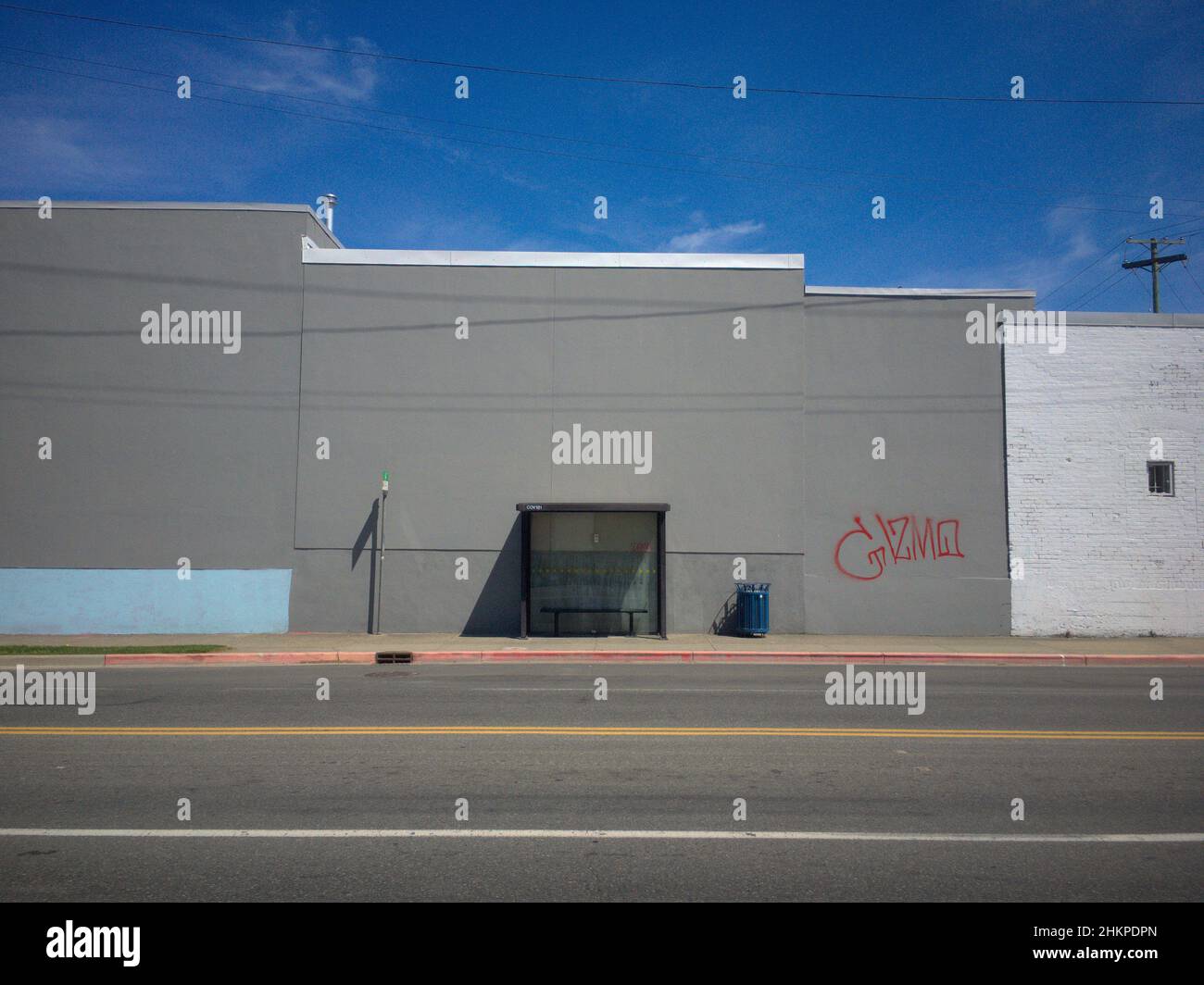 An empty bus shelter behind a warehouse building on a street in ...