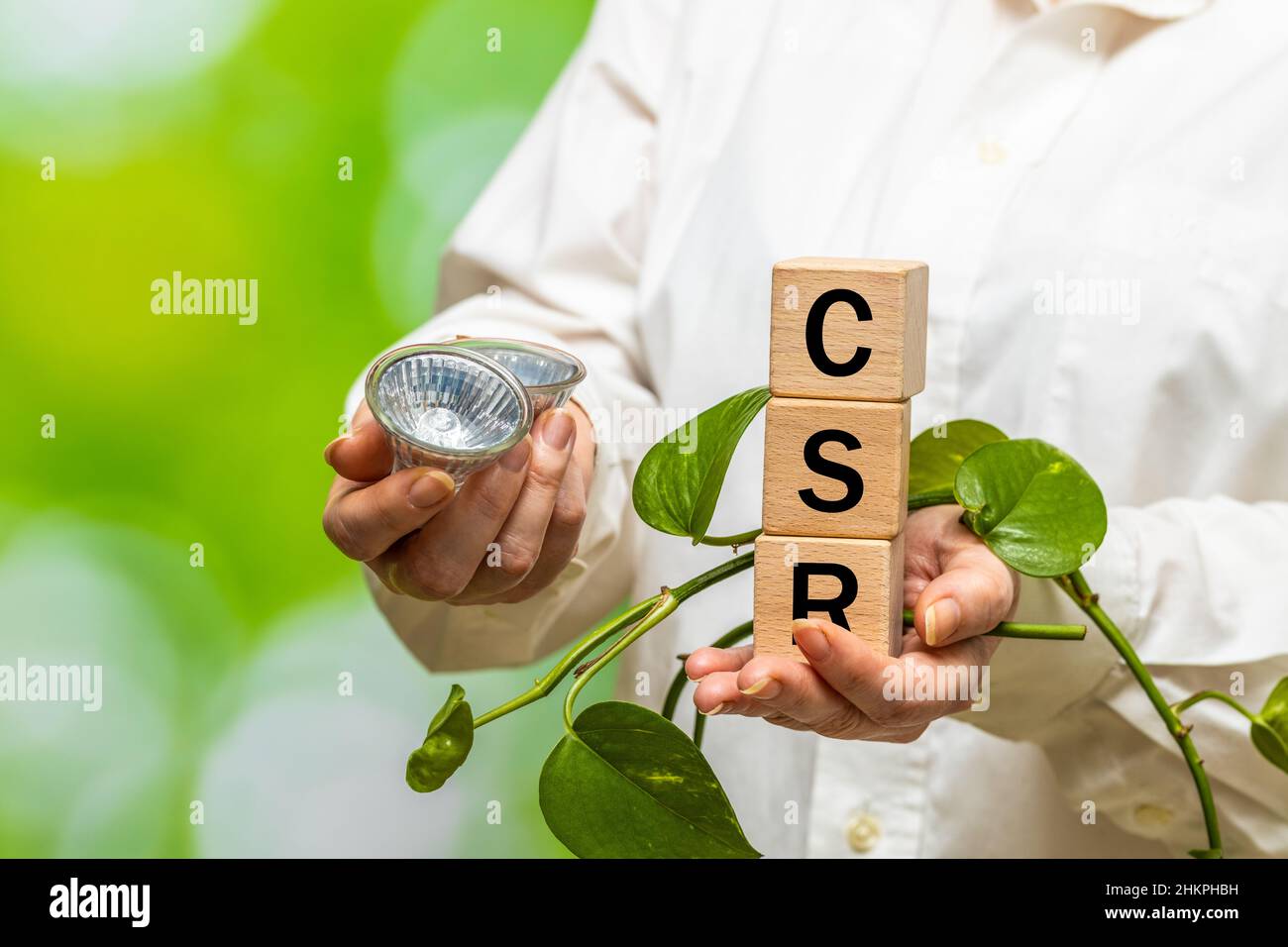 wooden blocks held in hand with the word CSR on a green nature ...