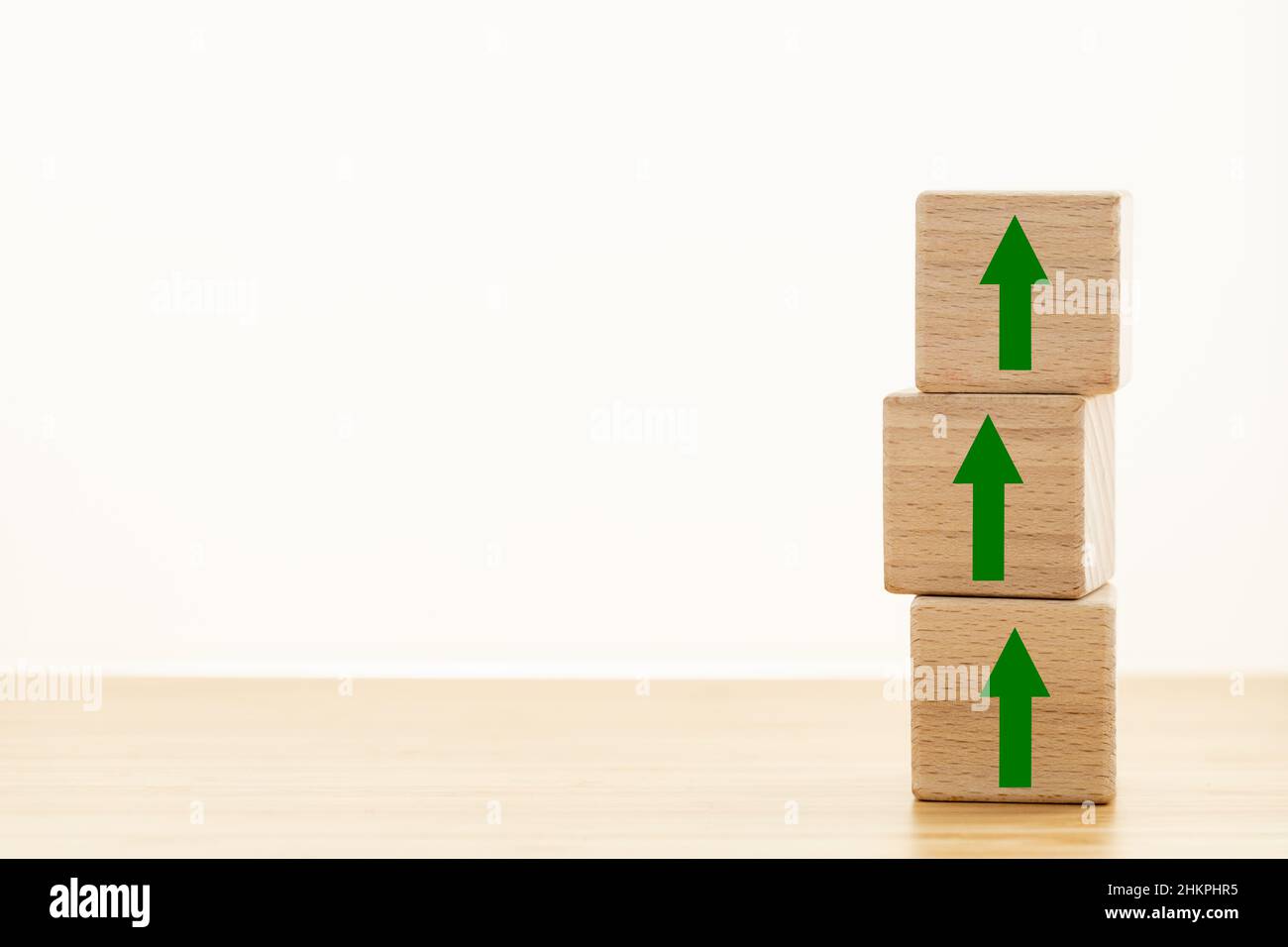 Wooden blocks lined up in a column with green arrows pointing upwards ...
