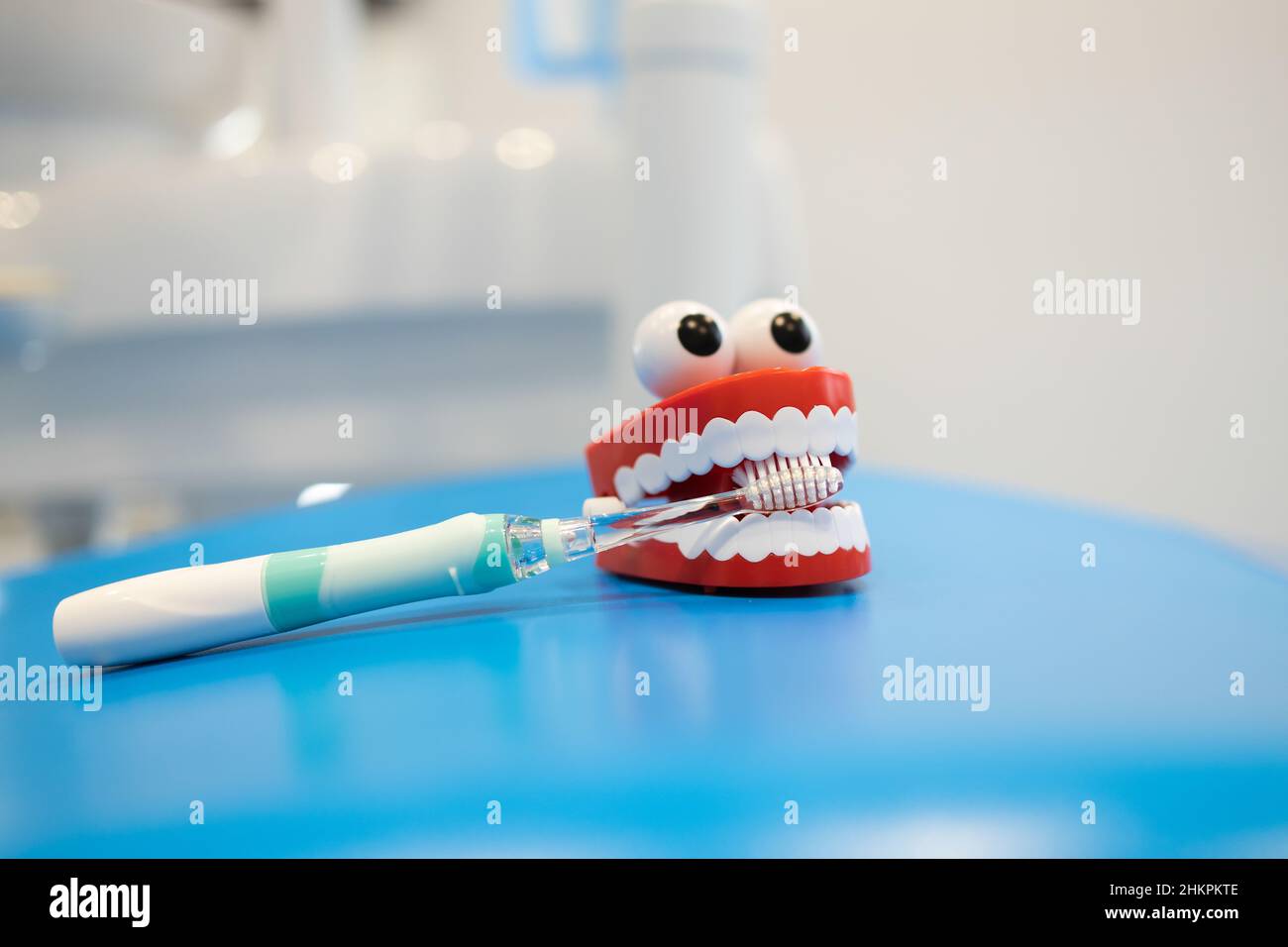 Toy clockwork jaw and a toothbrush lies on a blue dental chair in a ...