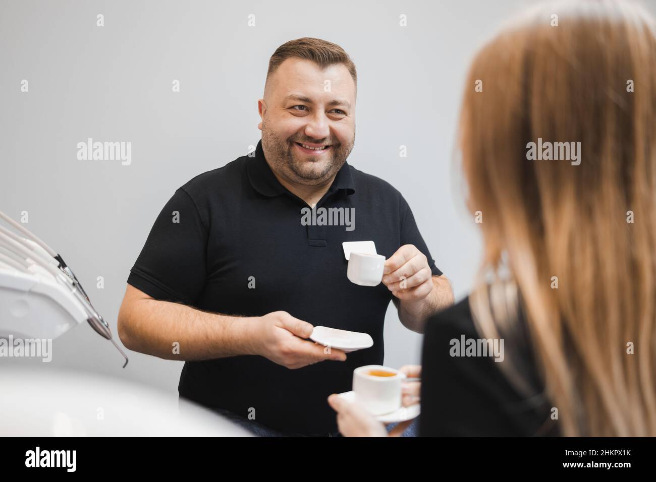 Male dentist and female patient having a conversation over a cup of ...