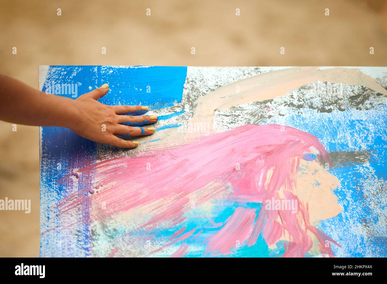 Woman hand smearing blue paint on canvas, art expression at outdoor art ...