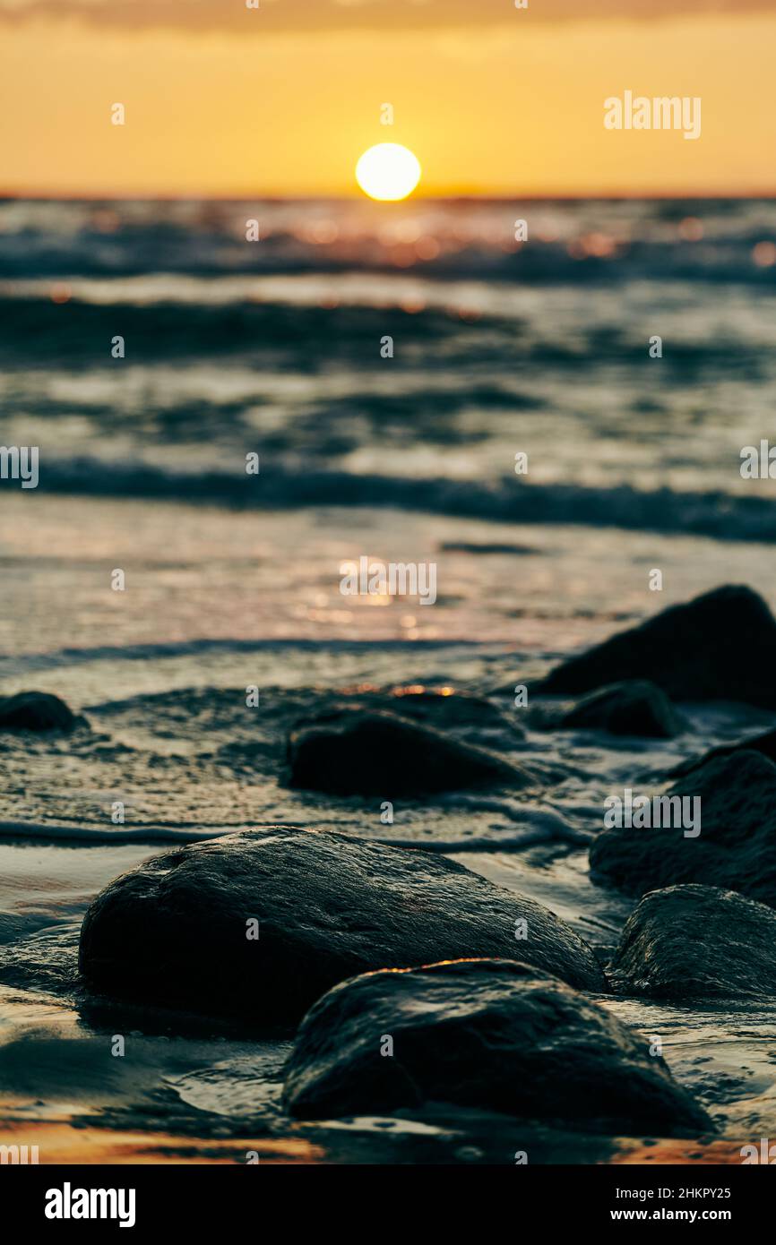 Yellow sun almost down horizon over deep blue sea at atmospheric sunset ...
