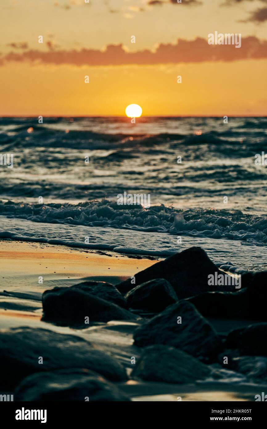 Yellow sun almost down horizon over deep blue sea at atmospheric sunset ...