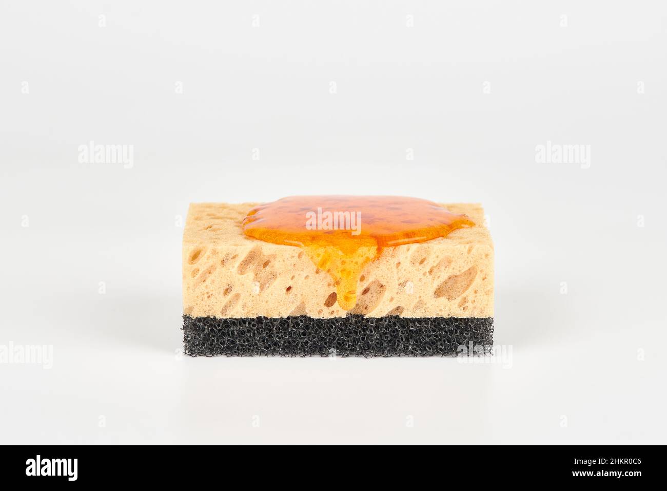 Orange detergent pouring onto yellow cleaning sponge isolated on white ...