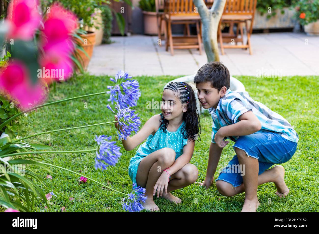 Two kids looking flowers on a garden Stock Photo - Alamy