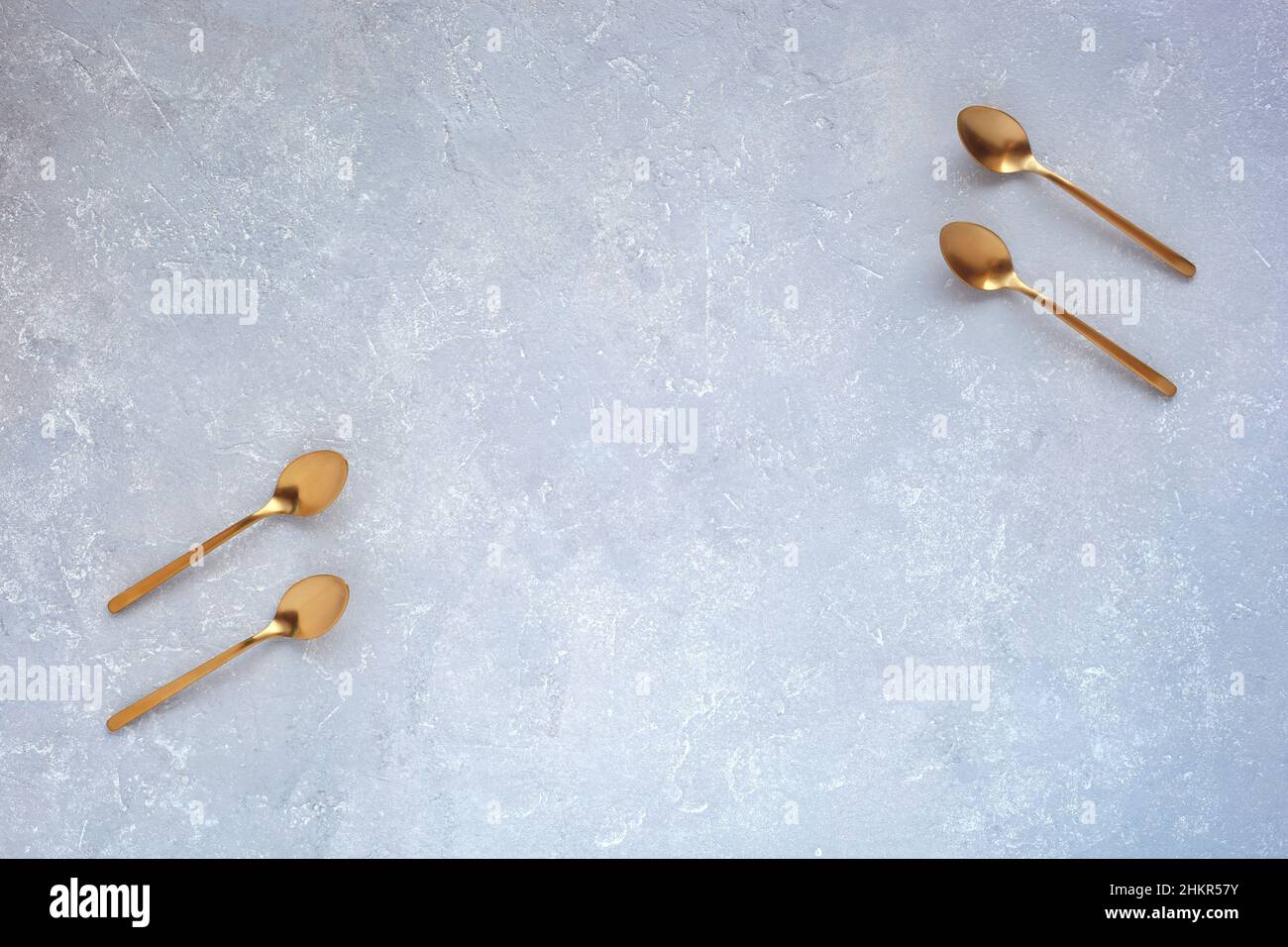 Two pair of spoons opposite each other on grey concrete background ...
