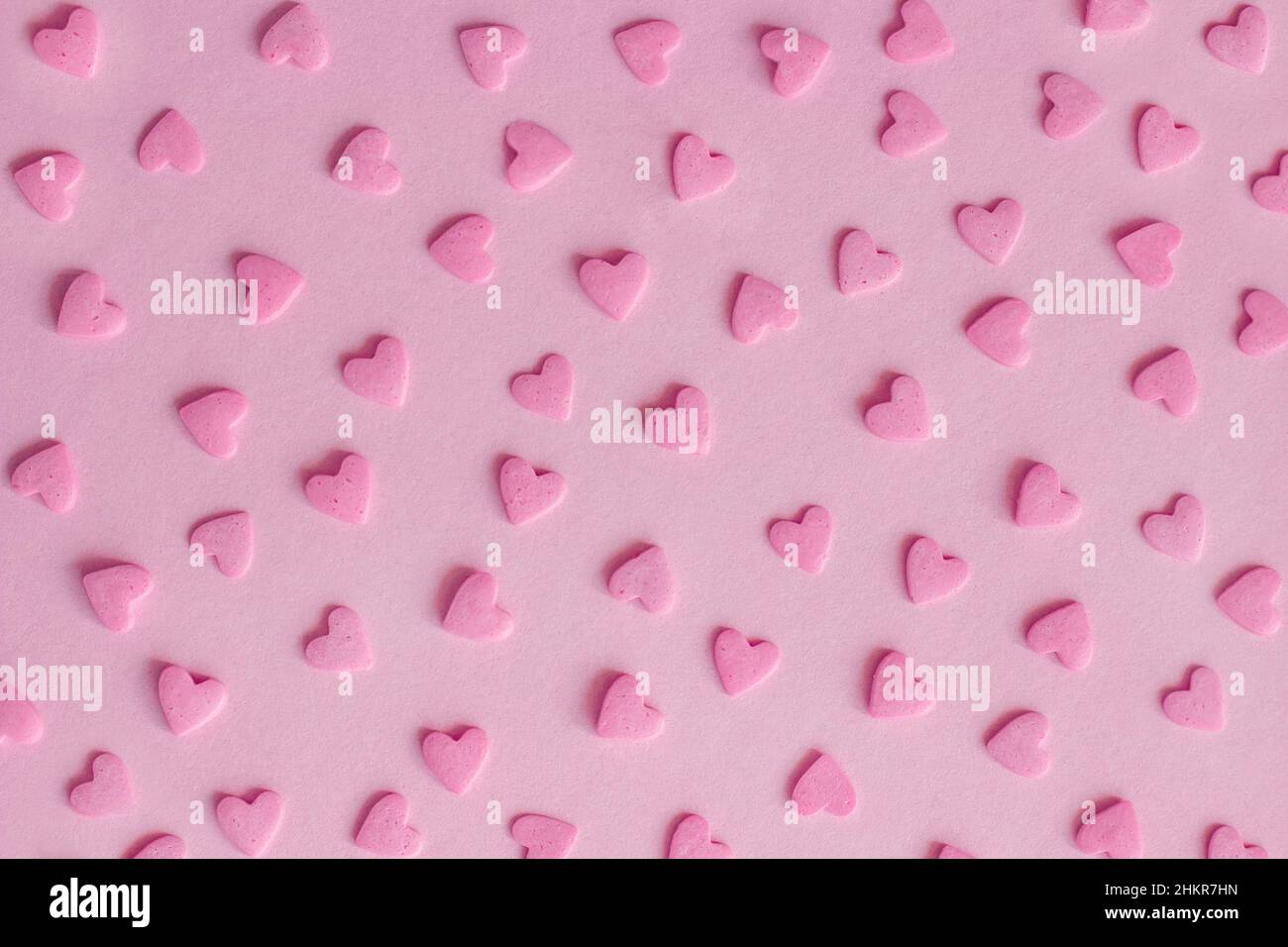 Pattern. Pink confectionery sprinkles in form of hearts on pink ...