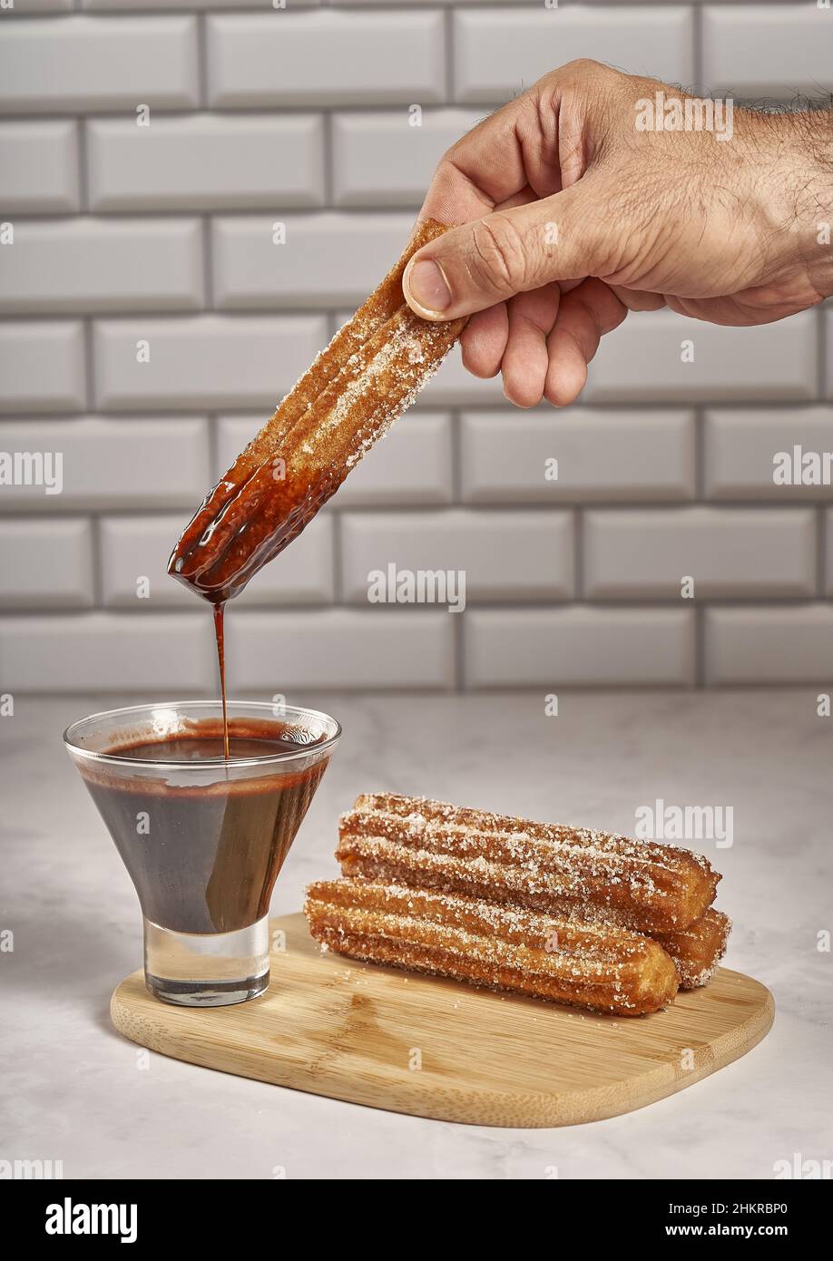Vertical shot of churro dipping in the chocolate sauce Stock Photo - Alamy