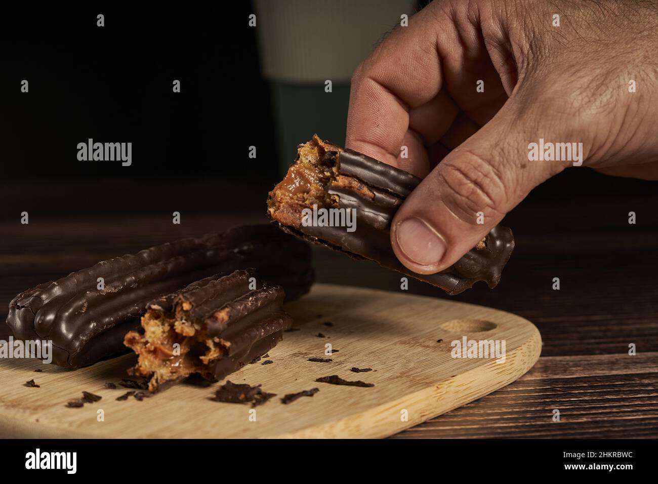 Shot of a hand holding half of a churro filled with dulce de leche and ...