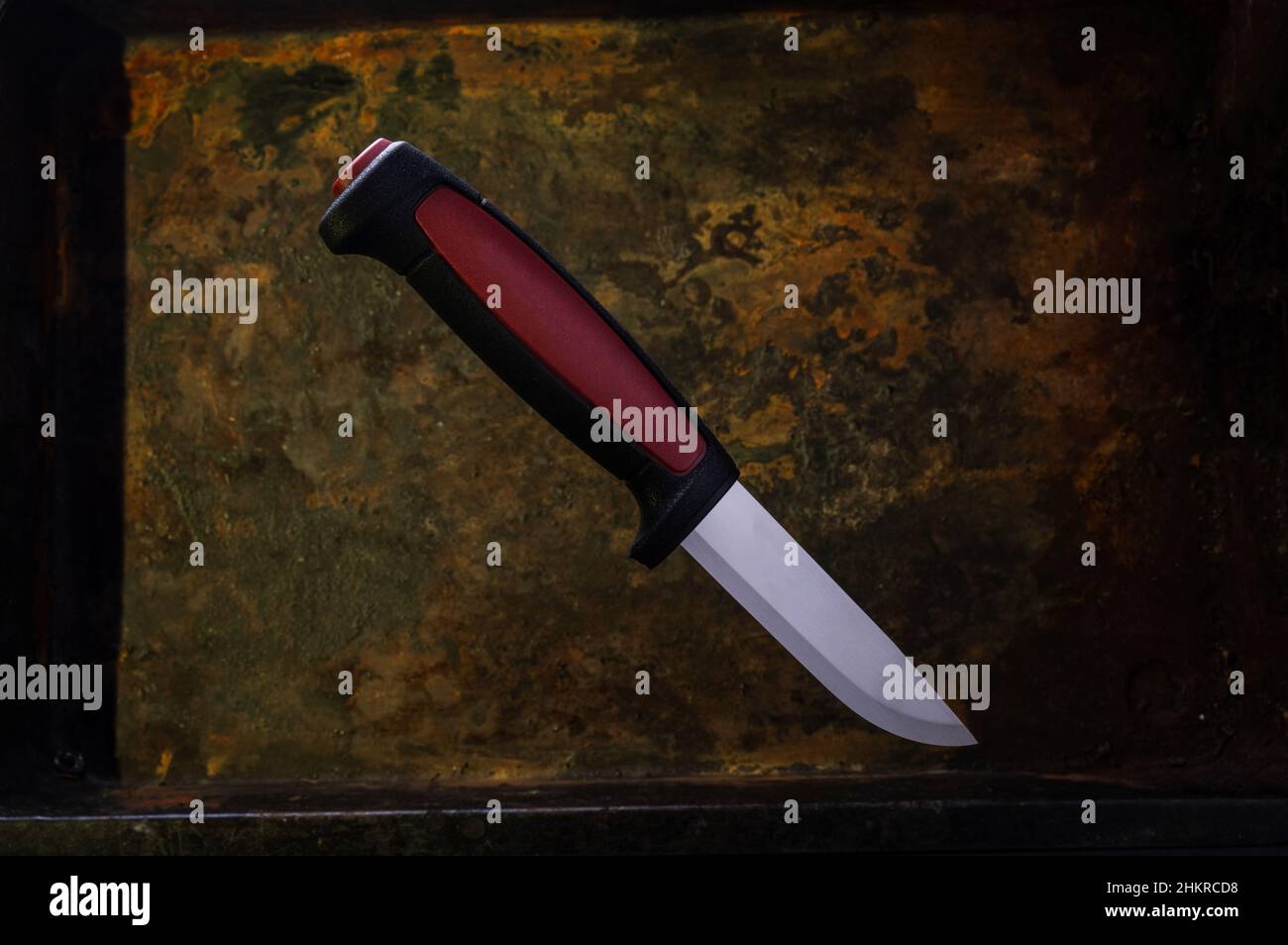 Fixed blade knife with red handle. Rusty background Stock Photo - Alamy