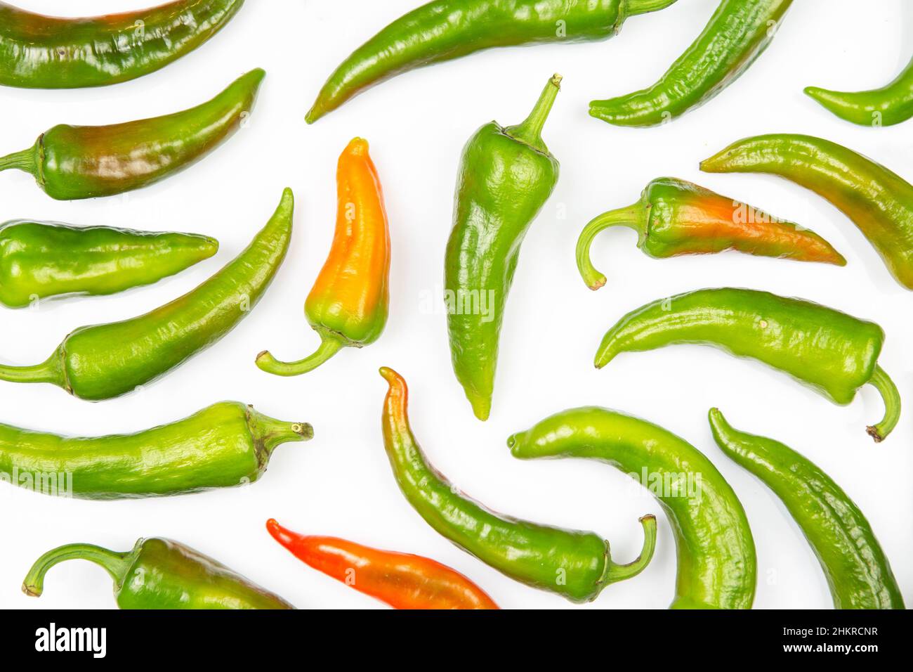 green hot peppers evenly spread on a white background. vitamin ...