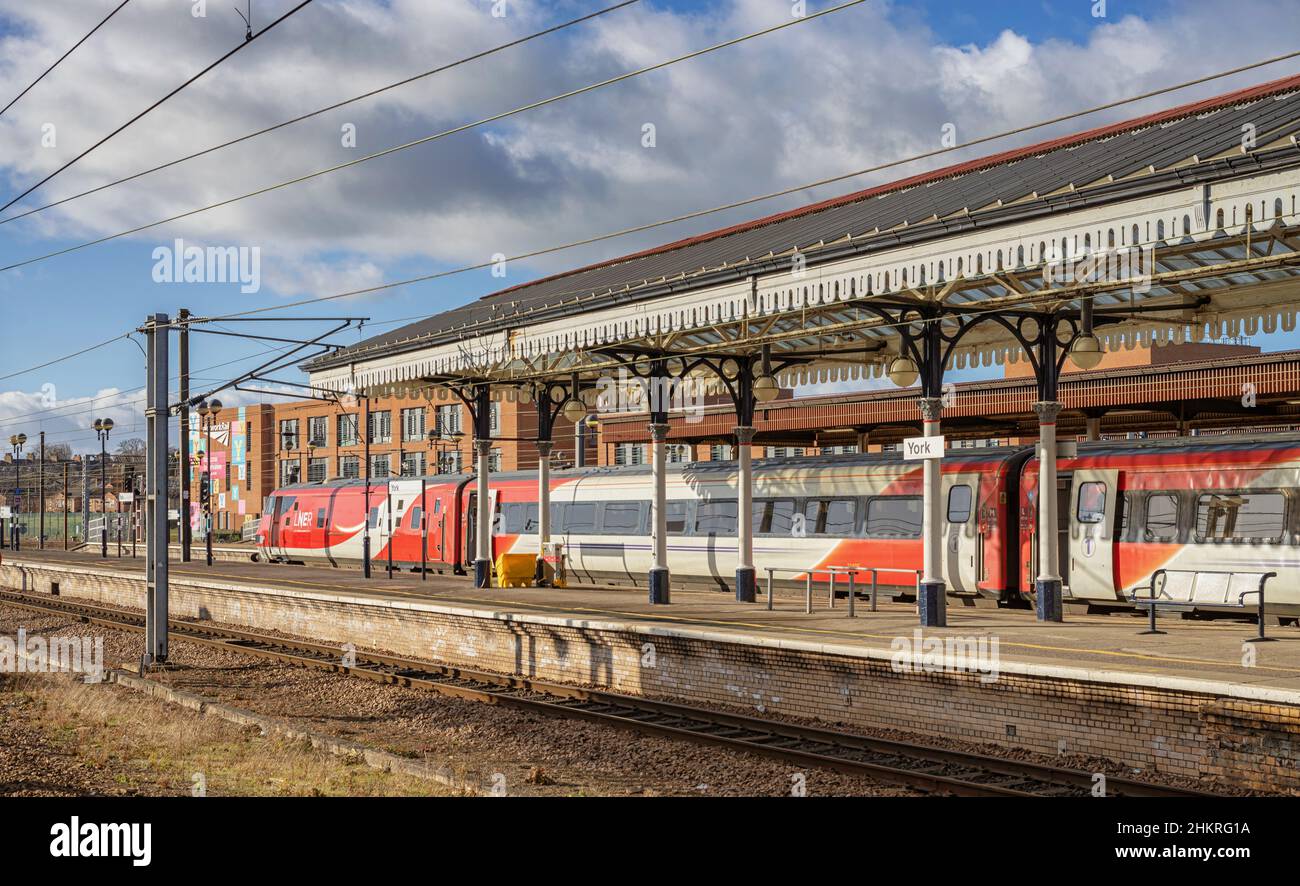 Railway station platform with a train alongside. Overhead is an ...