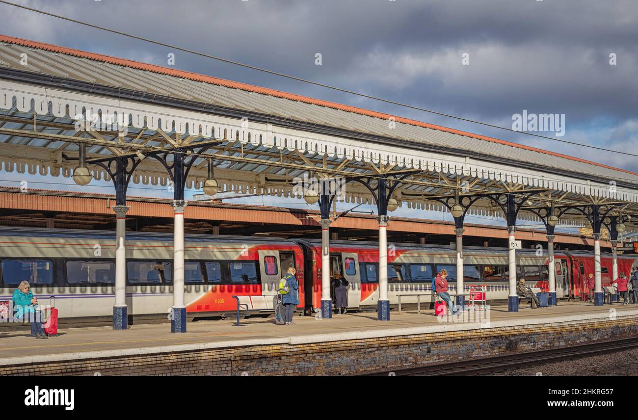 Railway station platform with passengers waiting for a train. Overhead ...