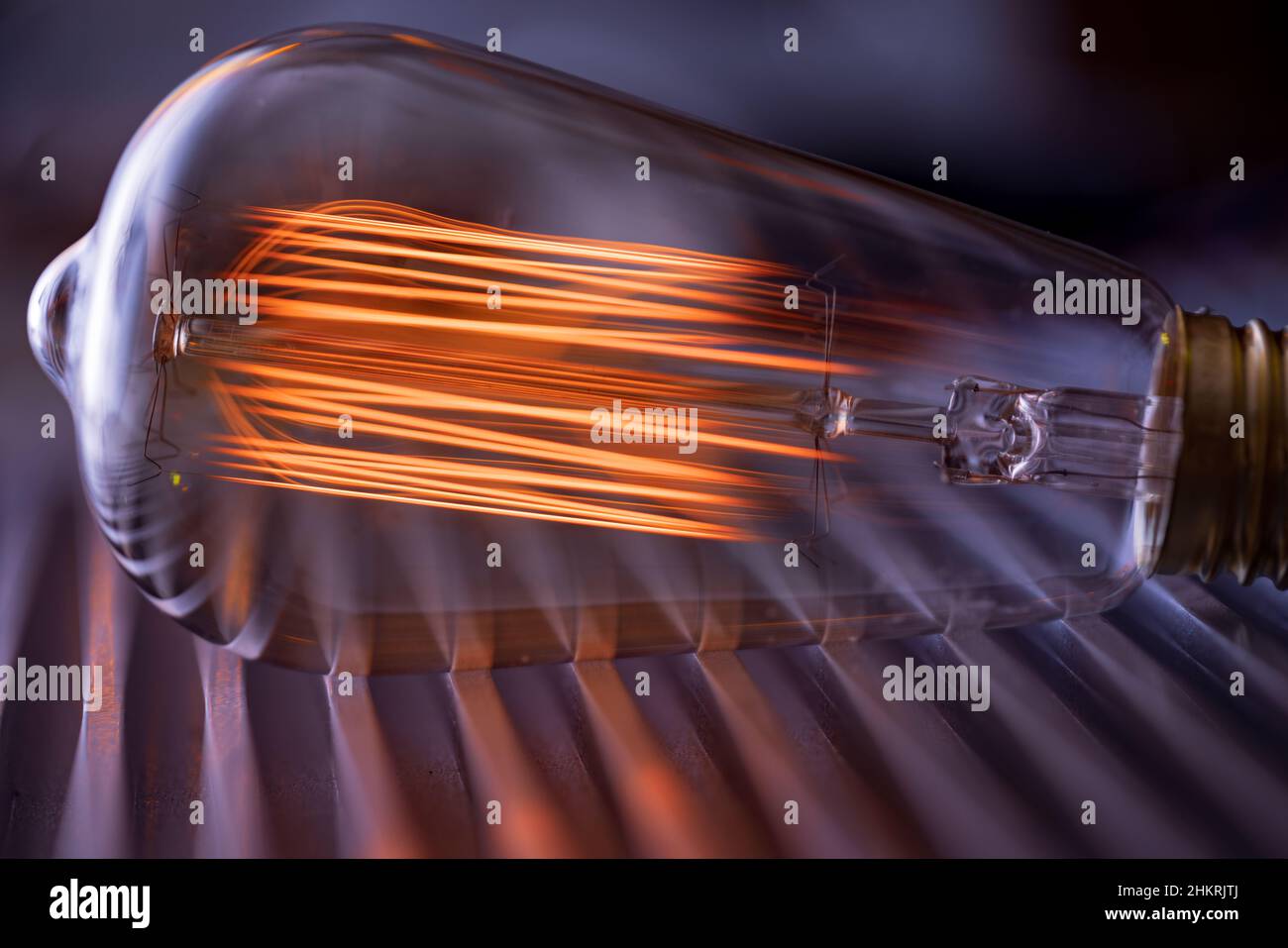 A bright fiery powerful glass incandescent lamp illuminates a dark room ...