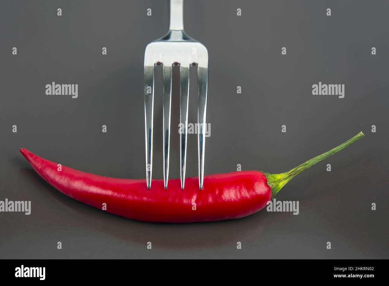 red hot pepper on a fork on a ceramic plate. spices and vegetative food ...