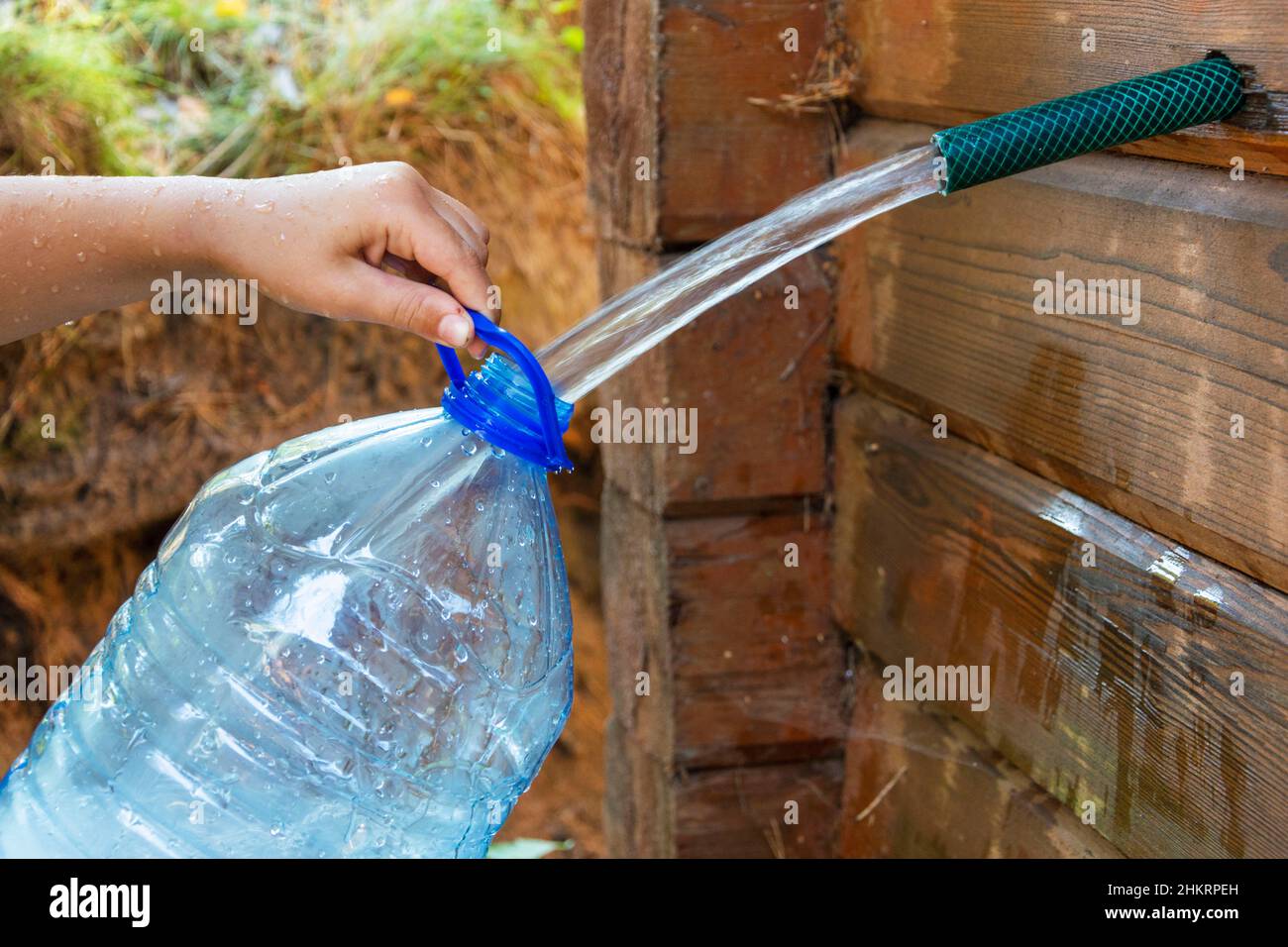 collecting natural spring water in a 5-liter plastic bottle, filling ...