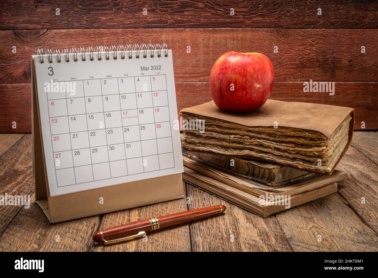 March 2022 - spiral desktop calendar with a stack of old book against ...