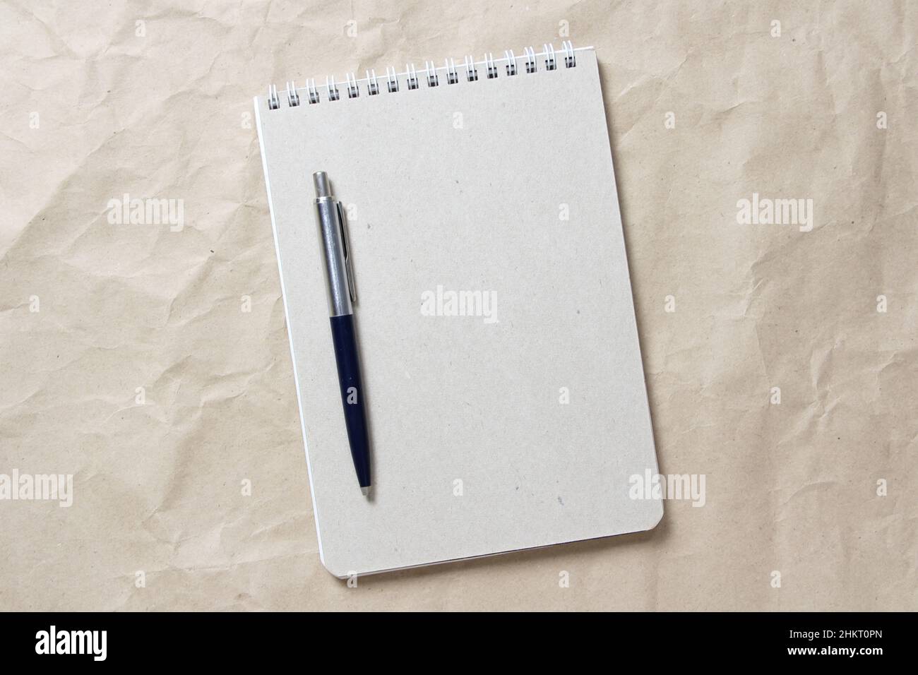 Gray notepad with white coiled spring and pen on a background of beige ...