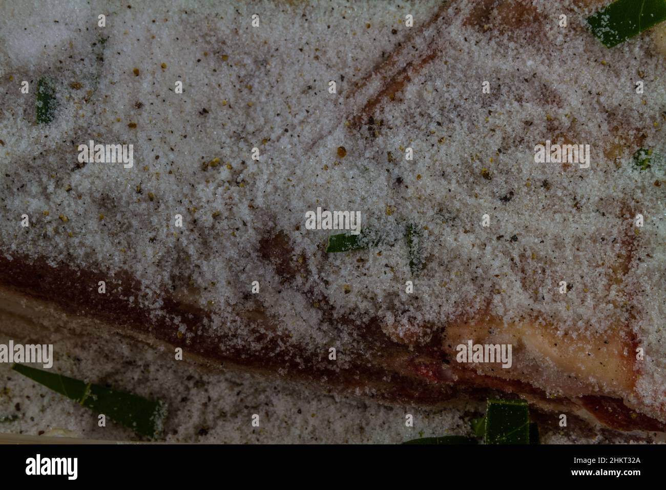 Close up of Dry salt cure on Pork belly joint at start of curing ...