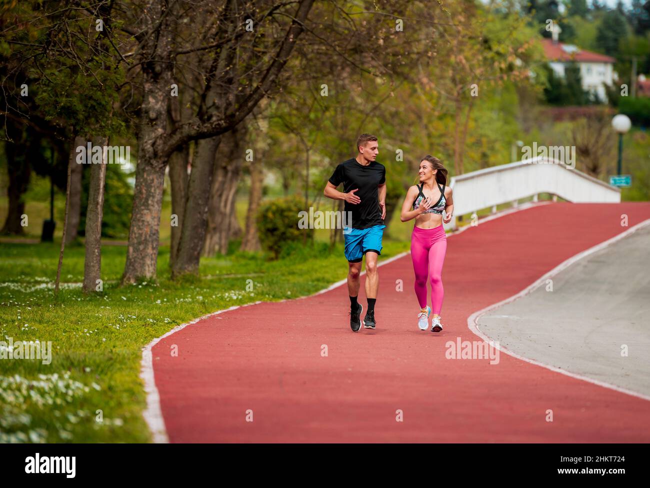 Beautiful young couple running on stadium track in stylish sportswear ...