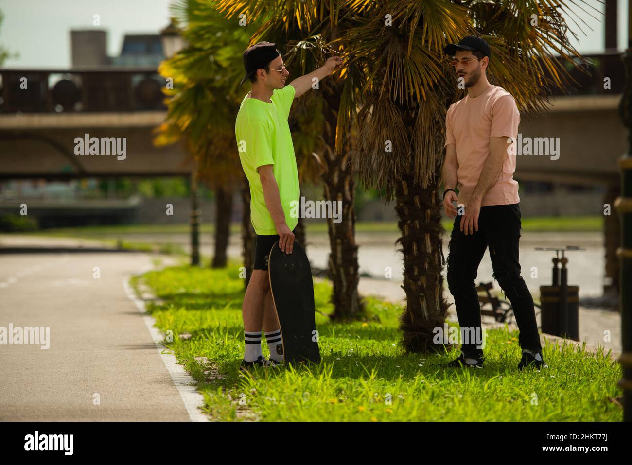 Two friends are going under the trees for shadow while talking about ...