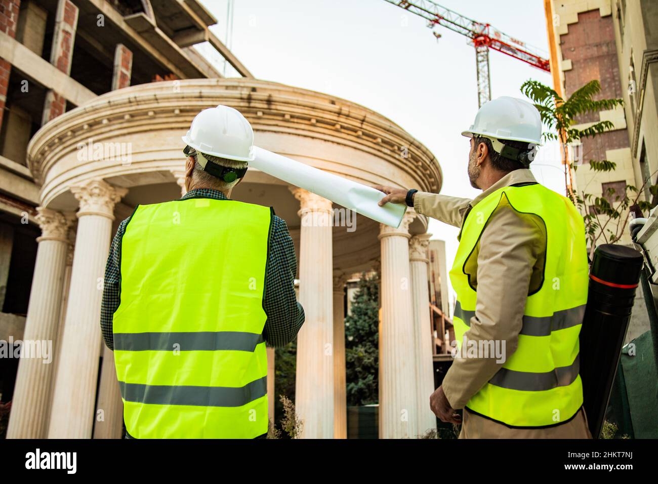 Two construction workers are looking at the construction area while ...