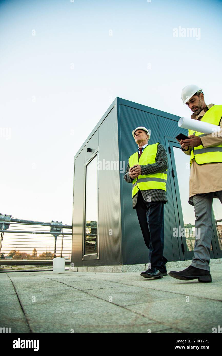 Two senior construction managers are walking together while talking ...
