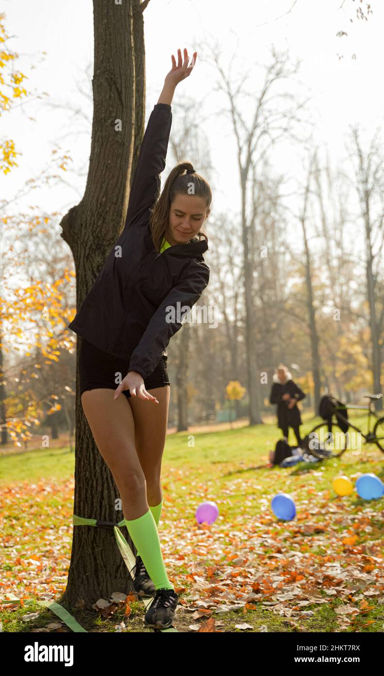Attractive and beautiufl fit girl is balancing on the rope and smiling ...