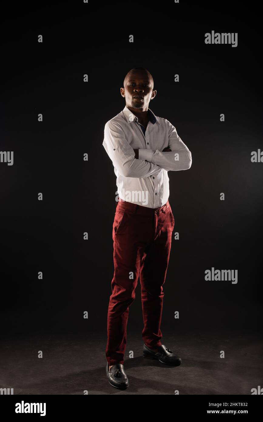 Well suited black businessman is posing in studio on dark background ...
