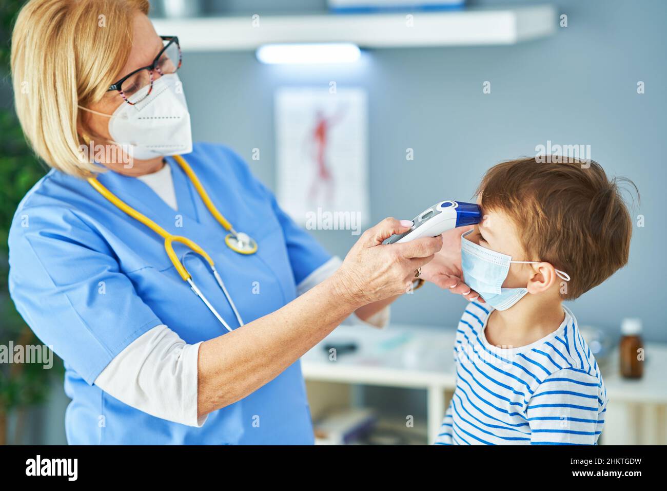 Pediatrician doctor examining little kids in clinic temperature check ...