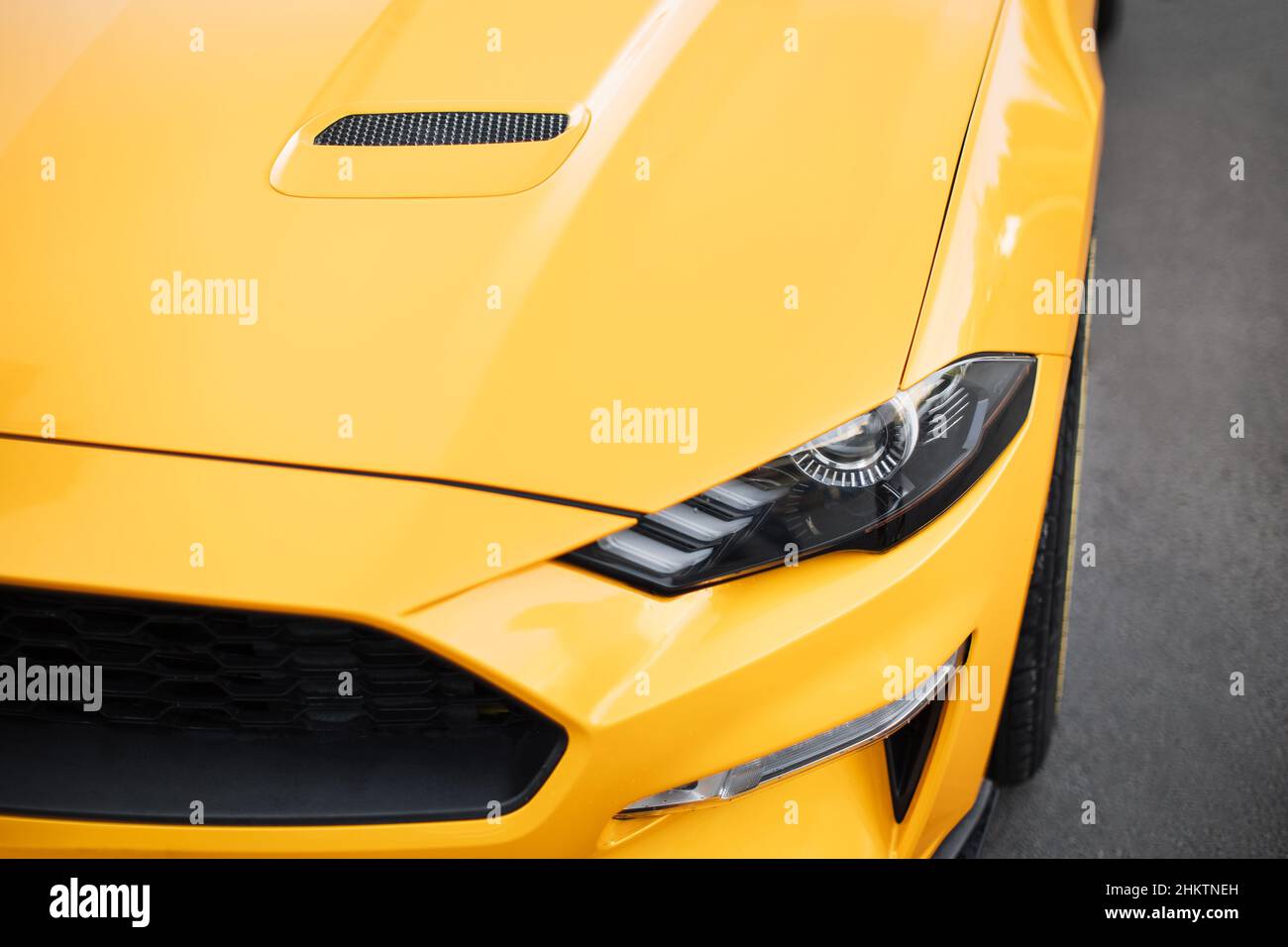 Close up detail on one of the LED headlights and car hood modern yellow ...