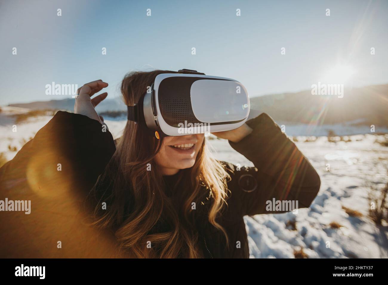 Young female looking through Virtual Reality glasses in the snowy ...
