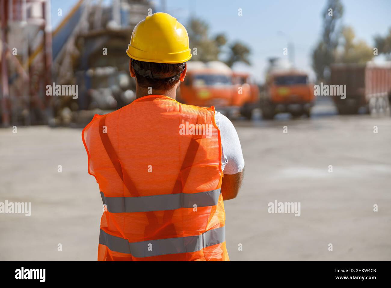 Confident construction worker controlling production process outdoors ...