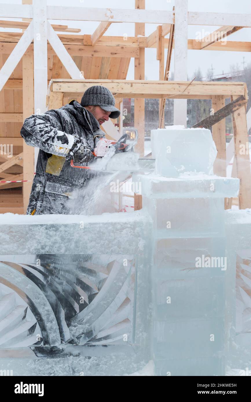 The sculptor cuts ice contours from ice with a chainsaw for Christmas ...