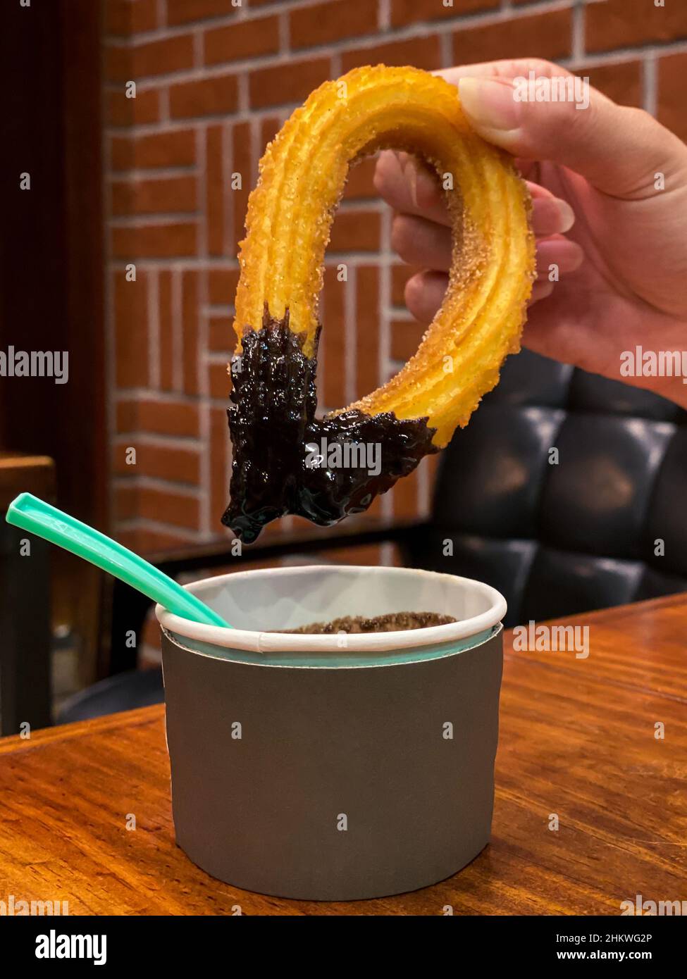 Woman eating a churro stick. Churros with sugar, chocolate and salted ...
