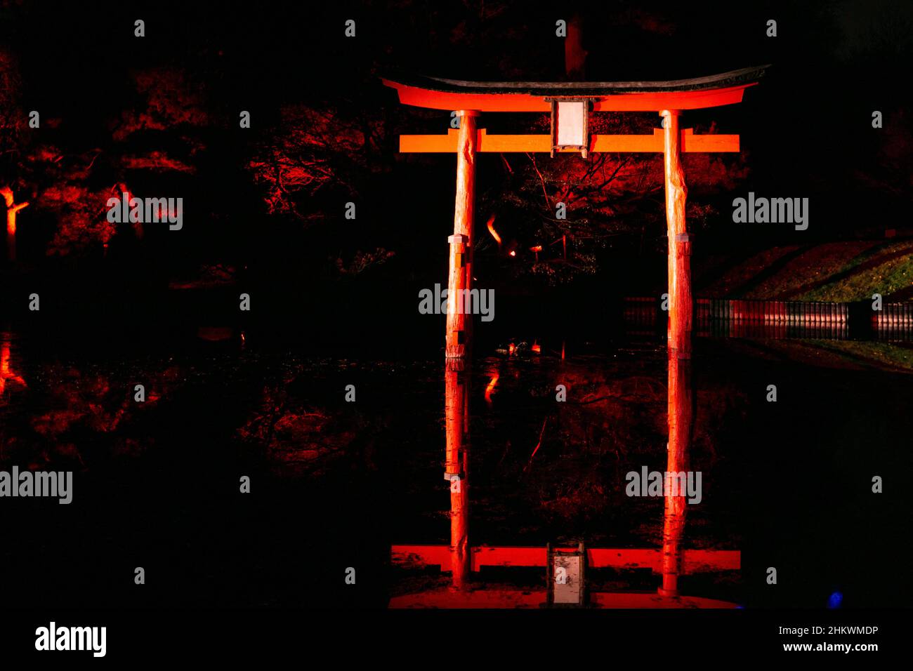 Japanese gate torii with reflection in water at night. Illuminated red ...