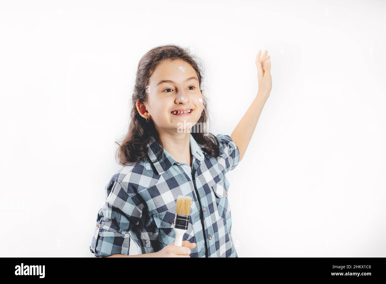 Positive pretty teenager girl having fun with paint brush. Portrait on ...