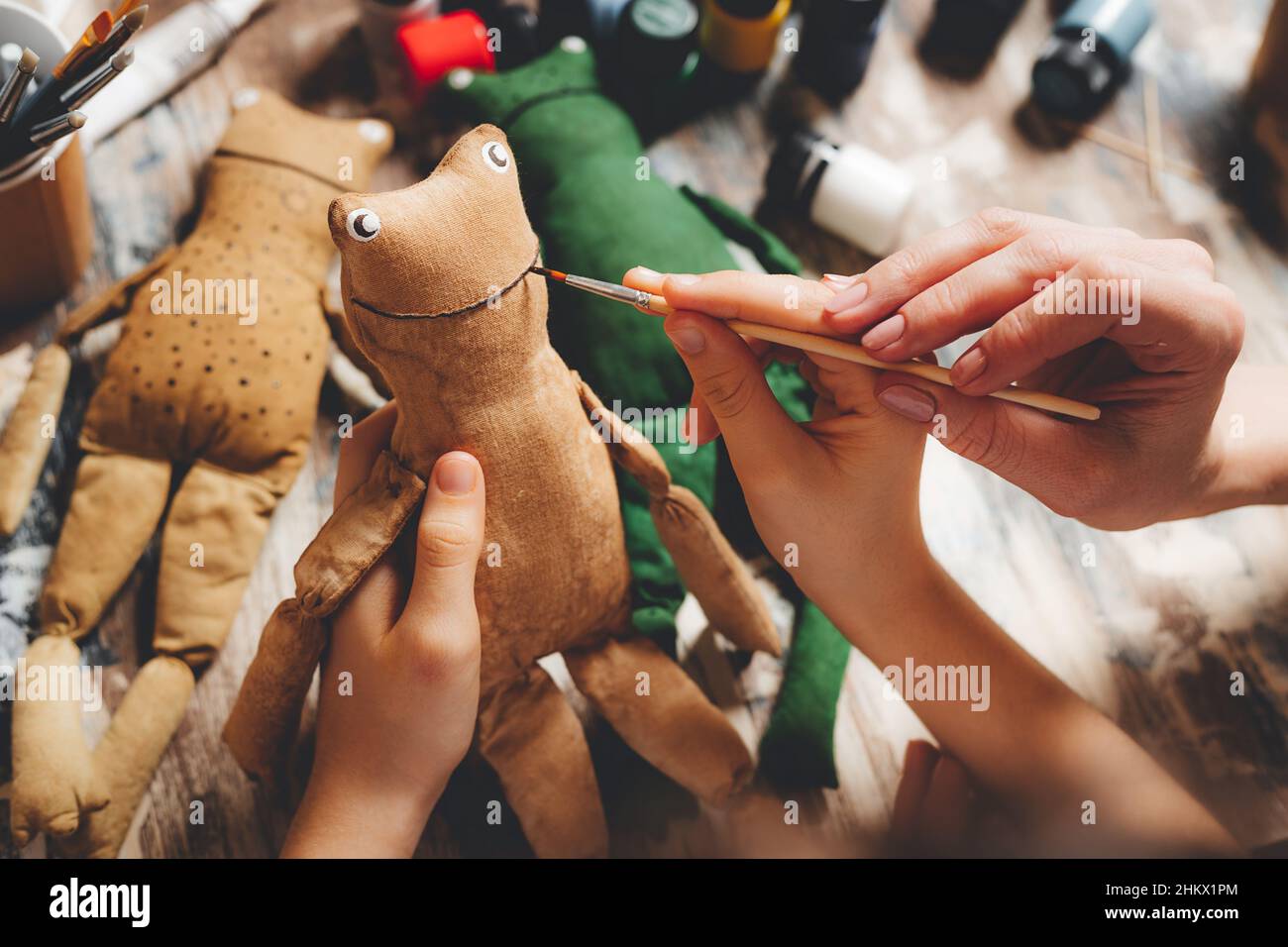 Hands of mother and child coloring handmade toy. Creativity together ...