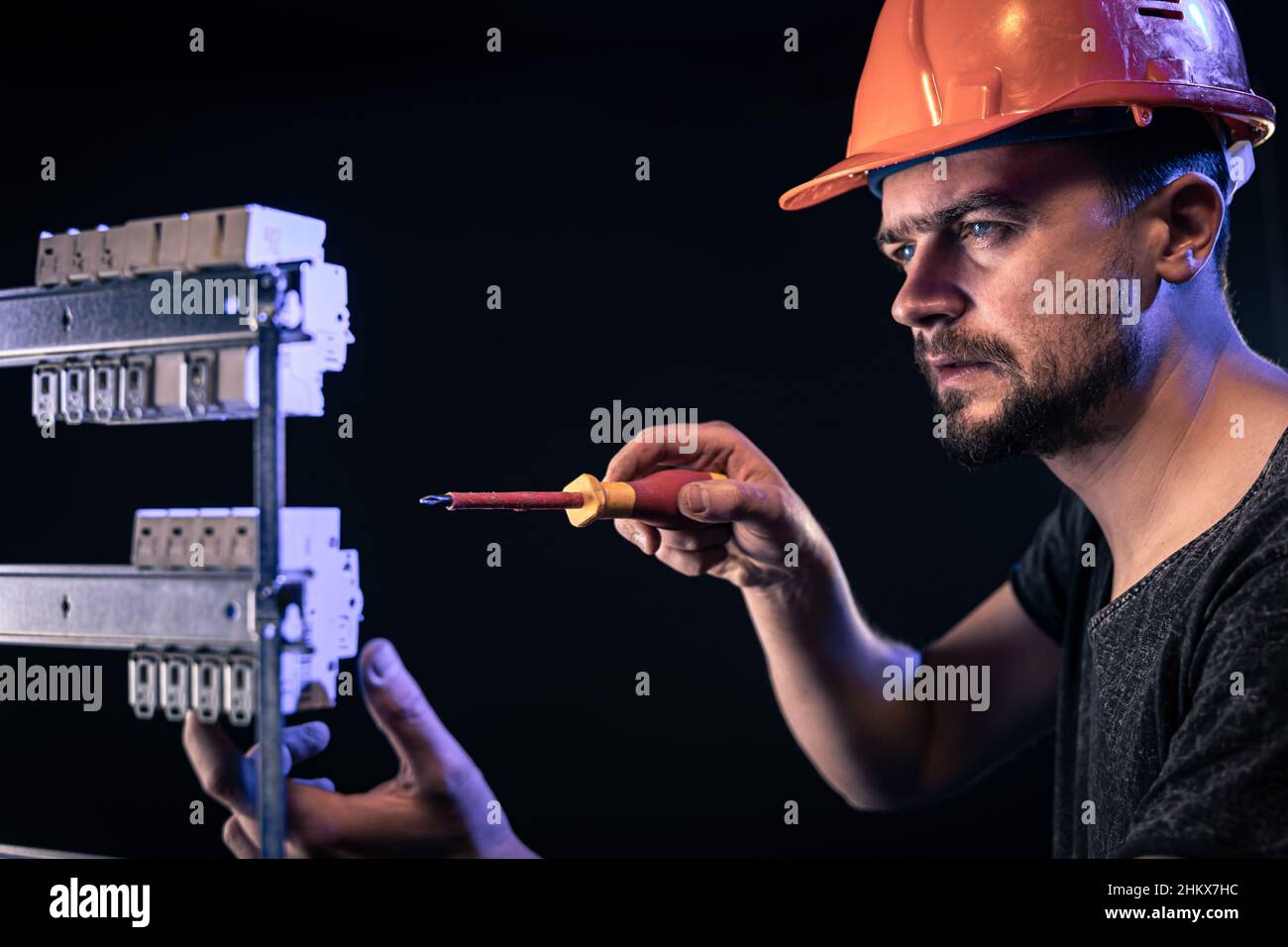 A male electrician works in a switchboard with an electrical connecting ...