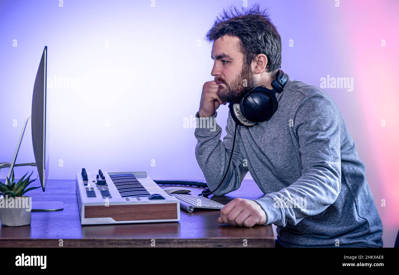 Male musician creates music using computer and keyboard, musician ...