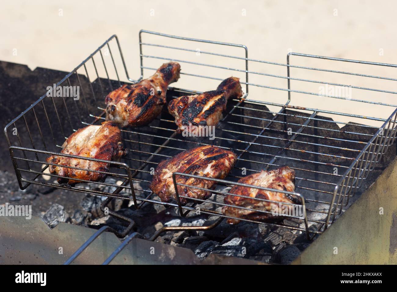 Grilled parts of chicken on the grill cooking on smoldering coal ...