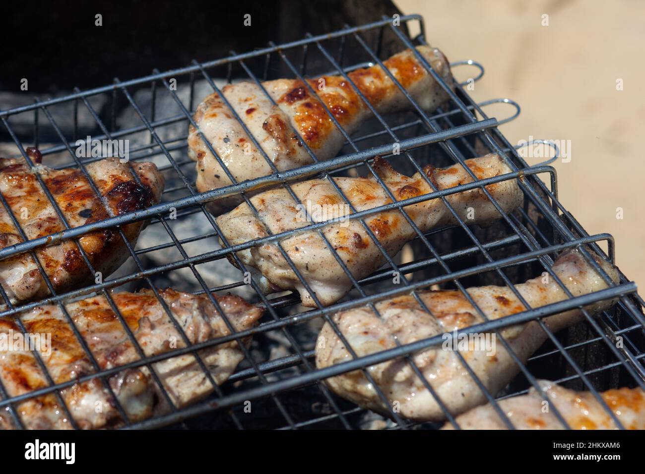 Grilled parts of chicken on the grill cooking on smoldering coal ...