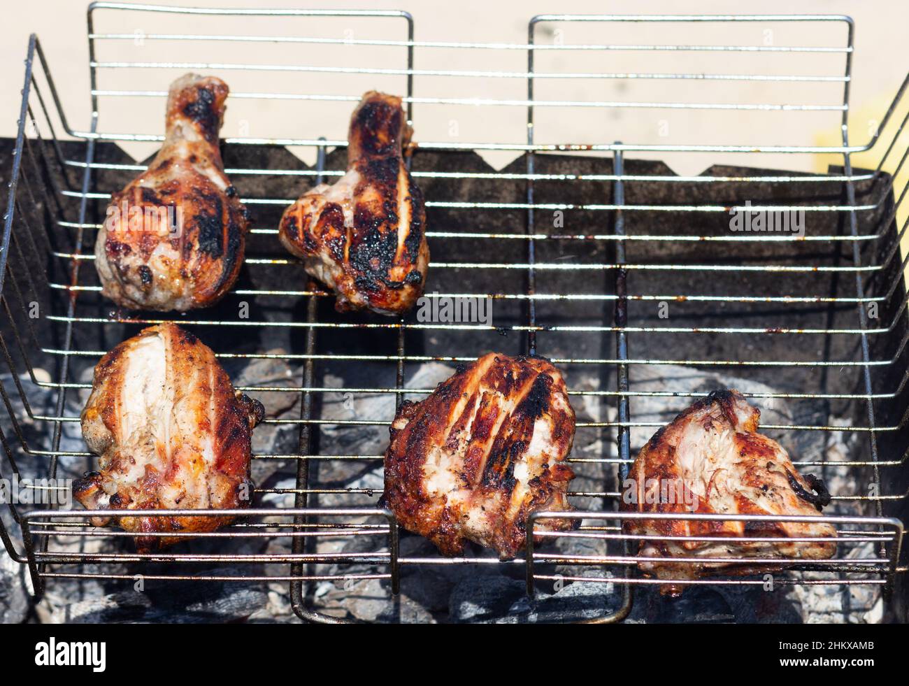 Grilled parts of chicken on the grill cooking on smoldering coal ...