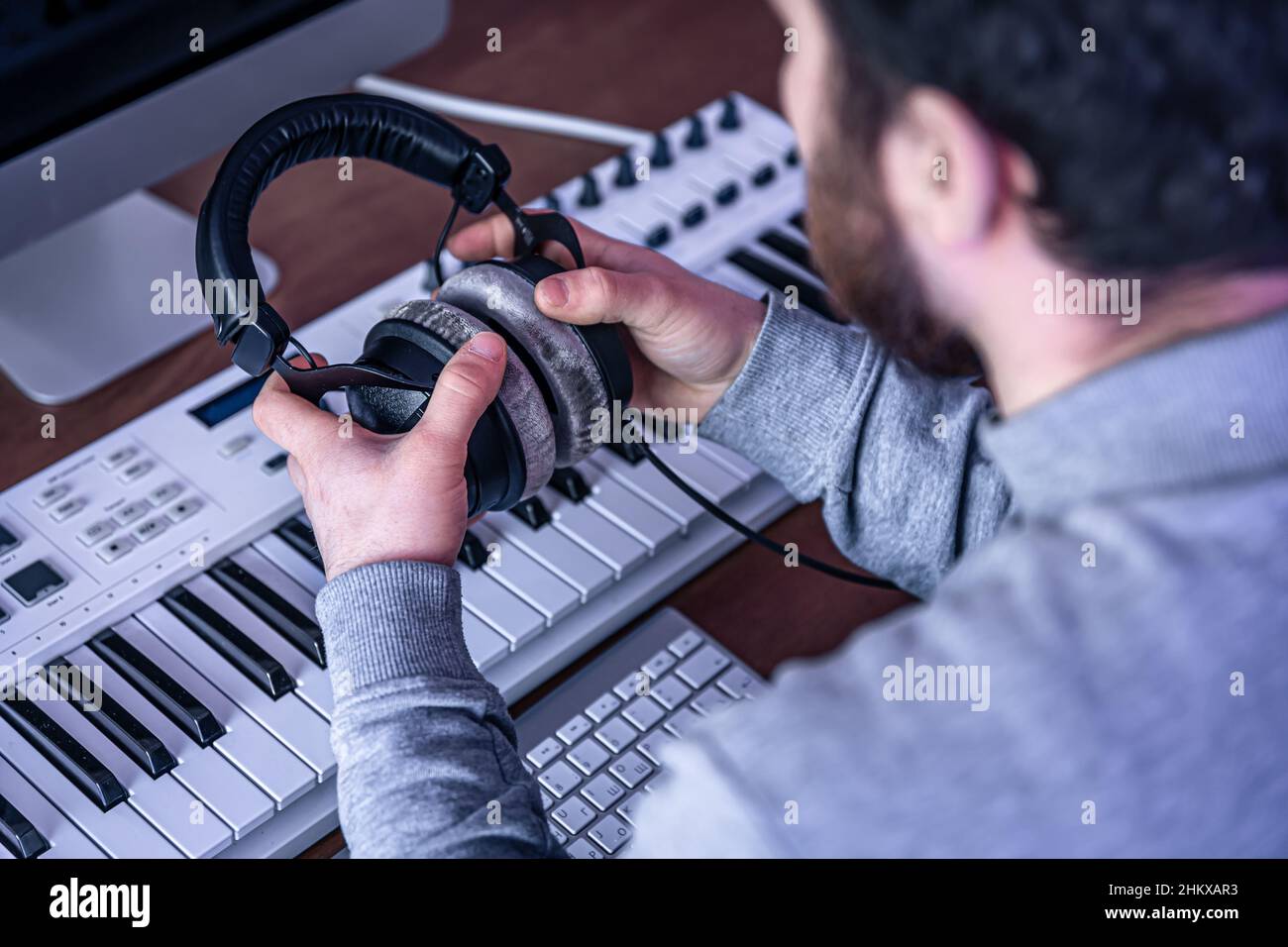 Male musician creates music using computer and keyboard, musician ...
