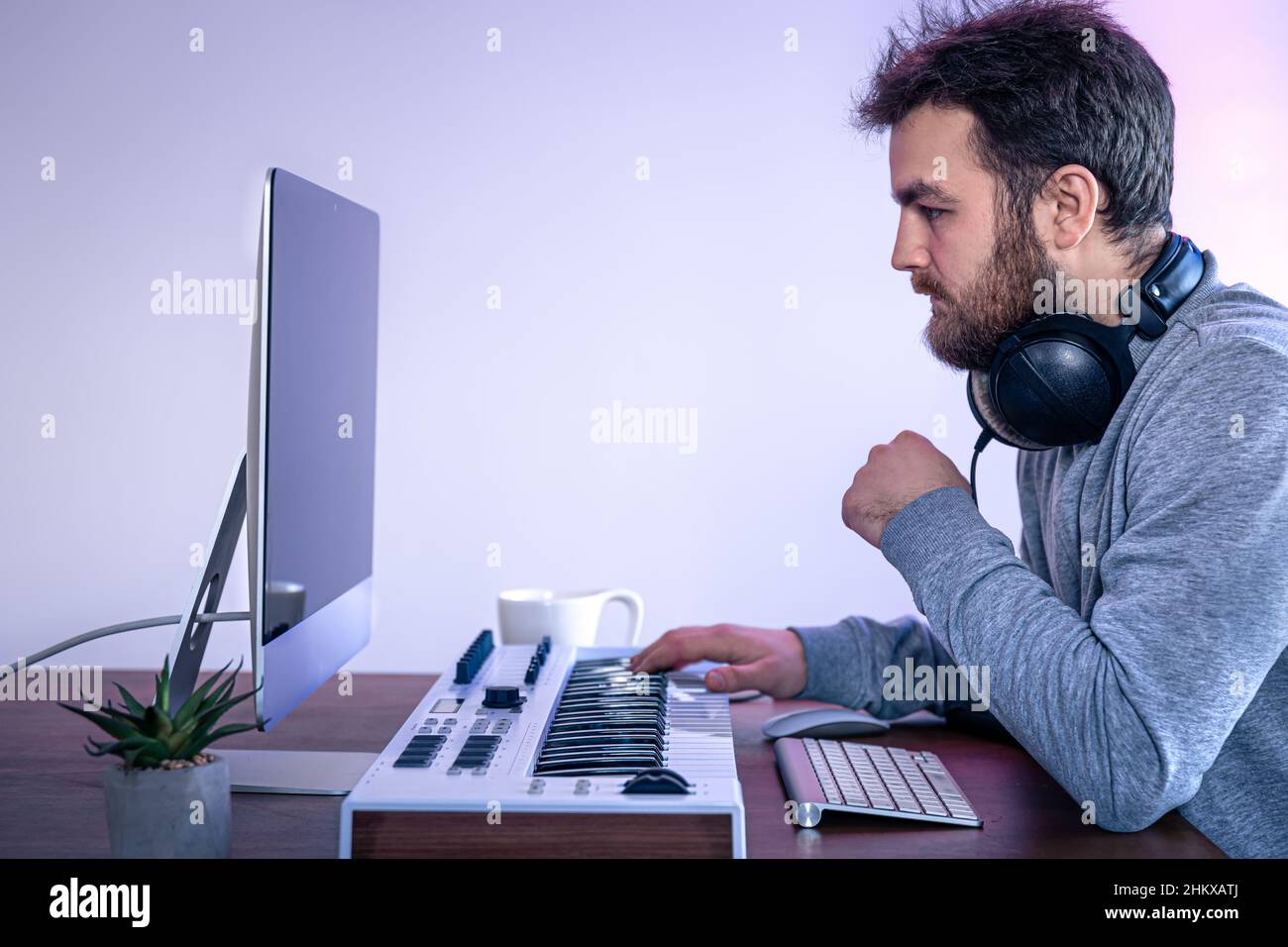 Male musician creates music using computer and keyboard, musician ...