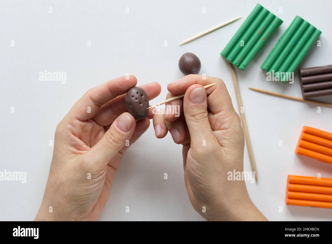 Woman hands making dots on the brown ball from polymer clay for create ...