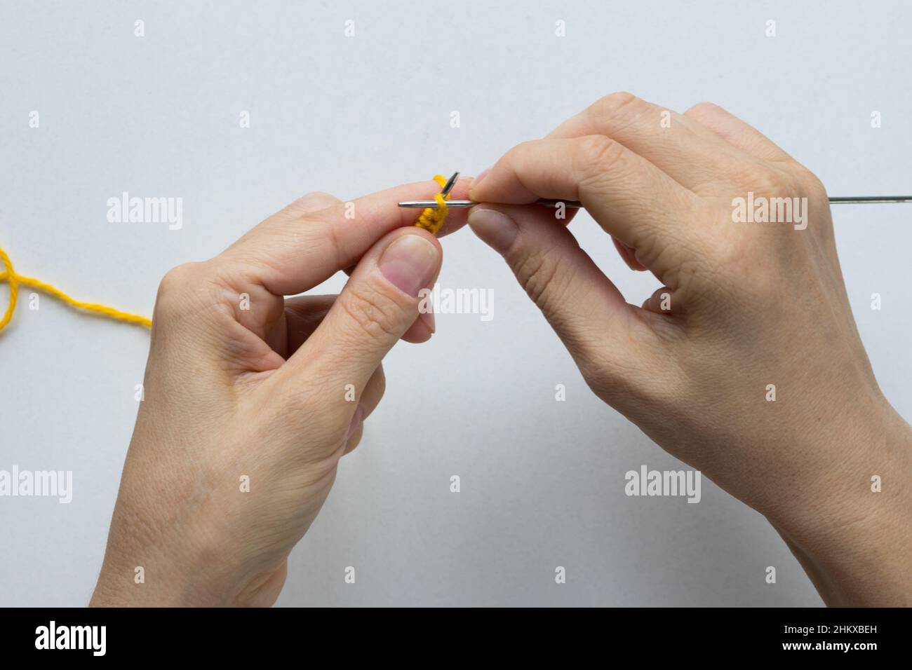 Knitting. Inserting right needle into first stitch to pull off left ...