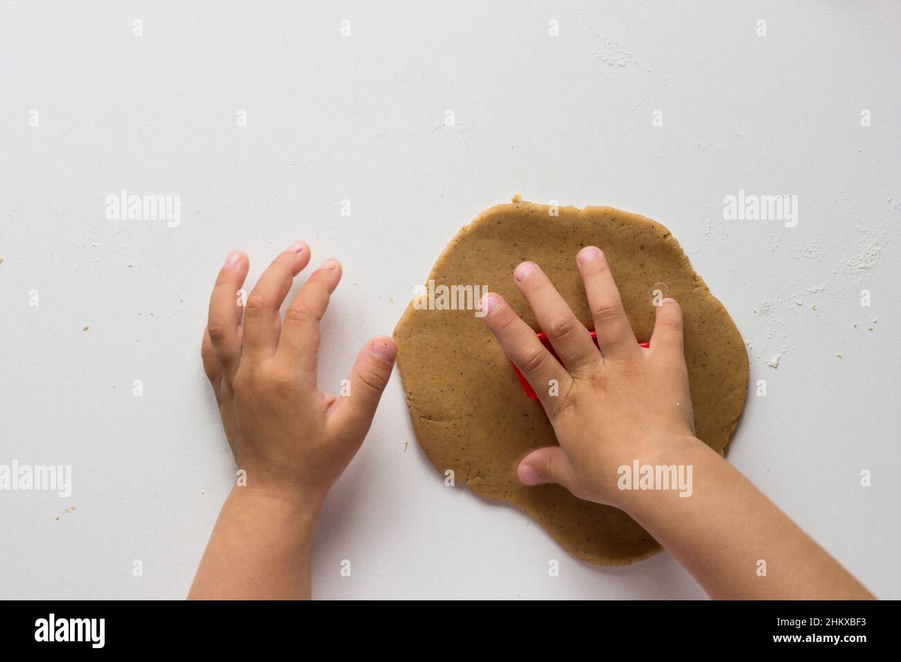 Child hands cutting forms on rolled out gingerbread dough on the white ...